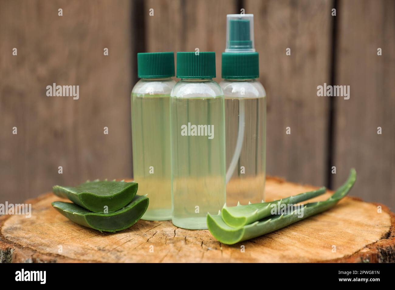 Bottles of cosmetic products and sliced aloe vera leaves on wooden ...