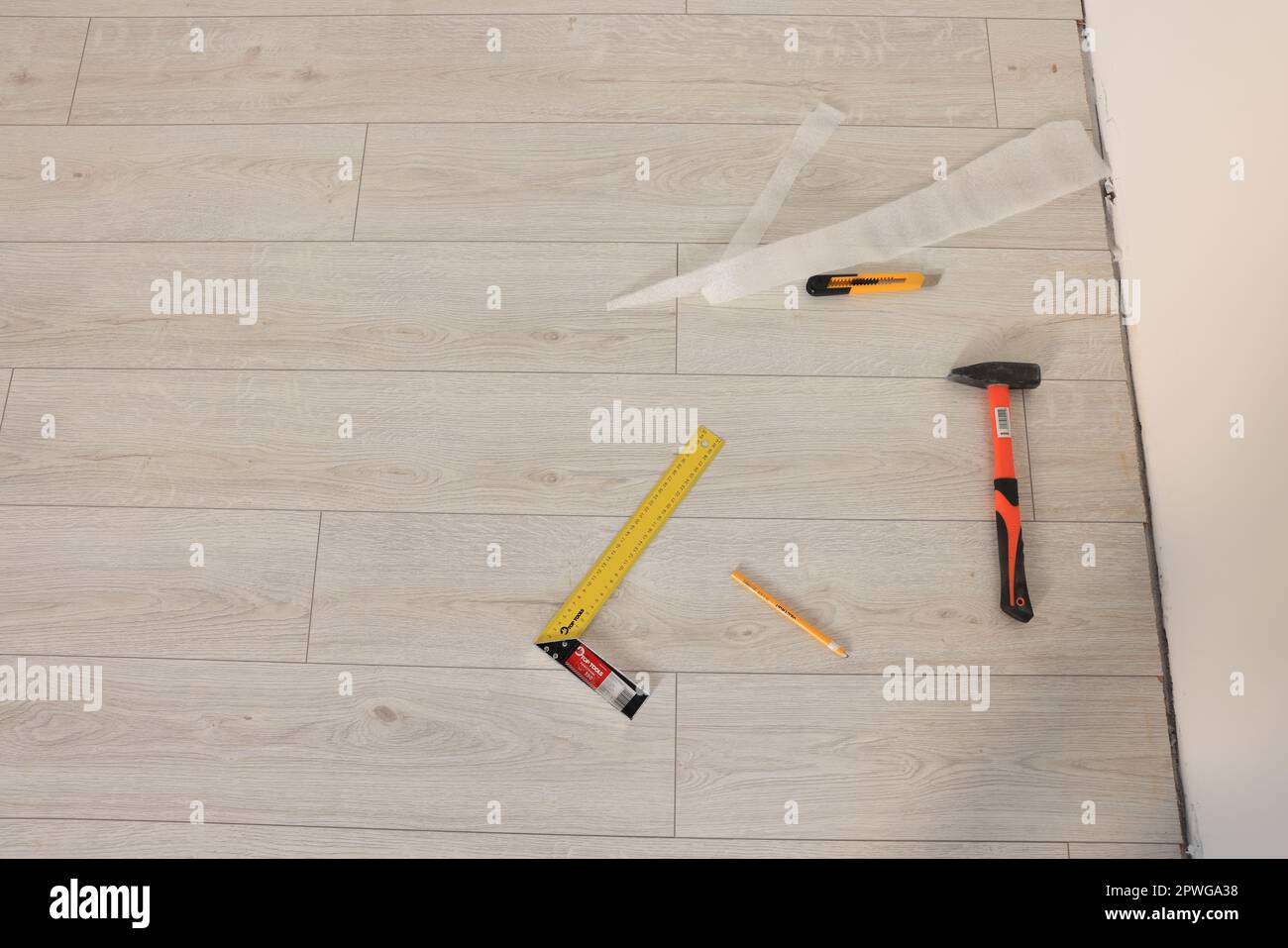 Hammer, cutter knife, pencil and ruler on laminated floor, flat lay ...