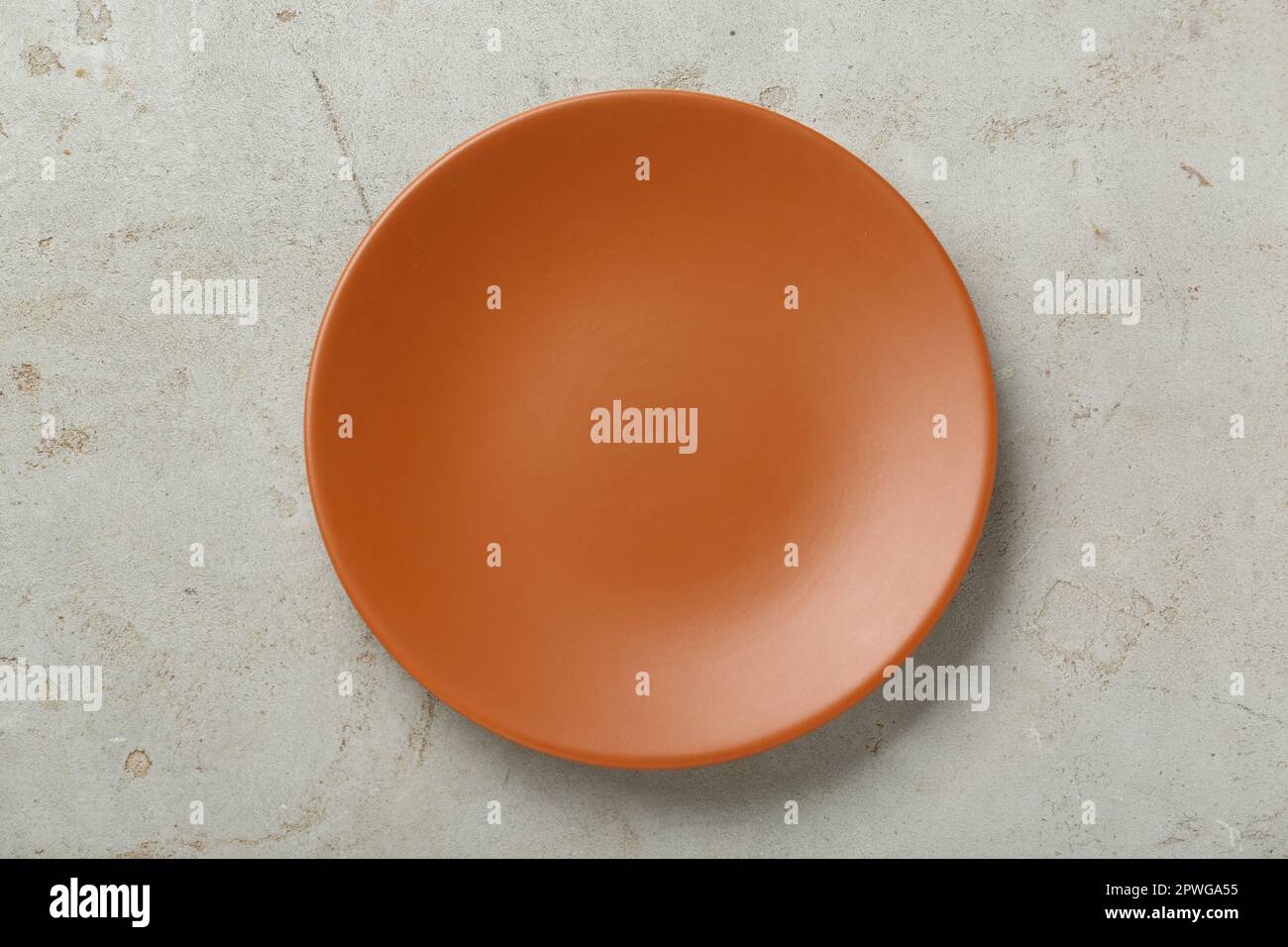 Empty orange ceramic plate on light grey table, top view Stock Photo ...