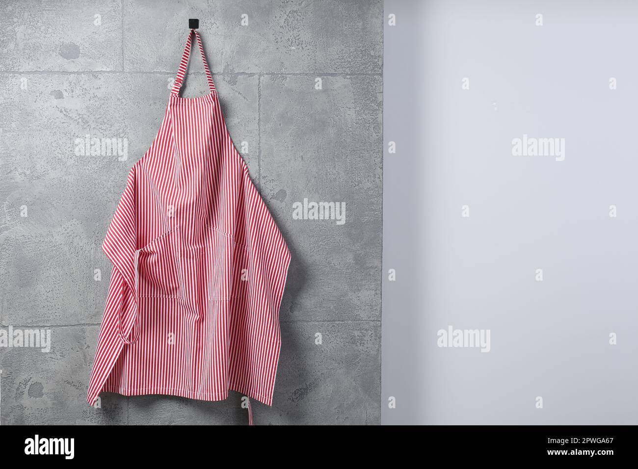 Clean red striped apron on grey tiled wall. Space for text Stock Photo ...