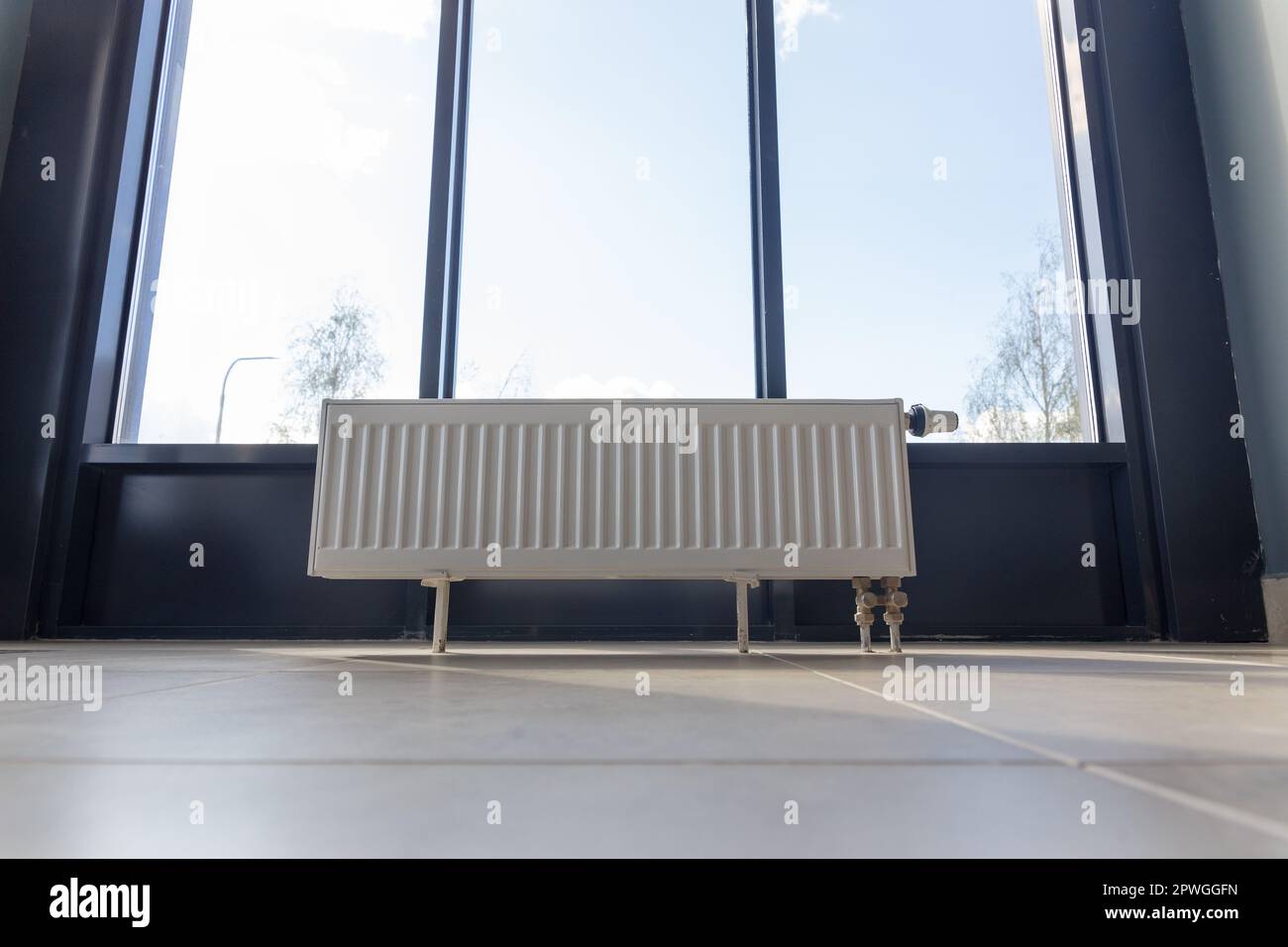 Vertically installed central heating radiator on the floor at the fully ...