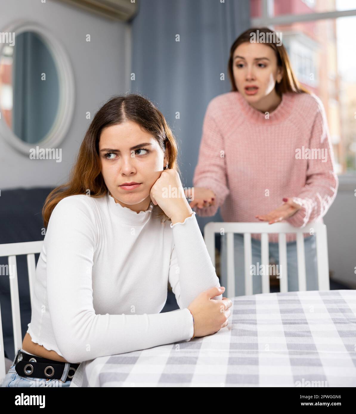 Upset woman sitting at home table with disgruntled woman behind Stock ...
