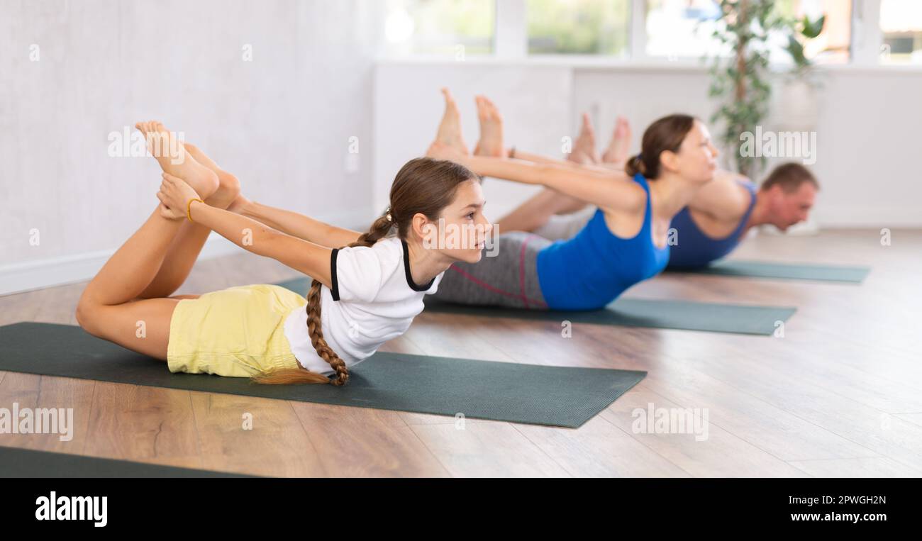 Teen girl doing back bending asana Dhanurasana known as Bow Pose during ...