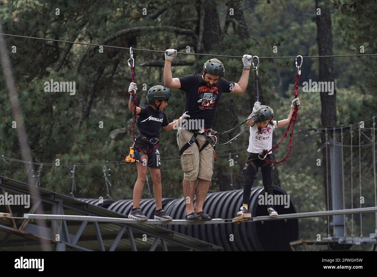 A parent plays on a cable bridge with his children at the Picacho ...