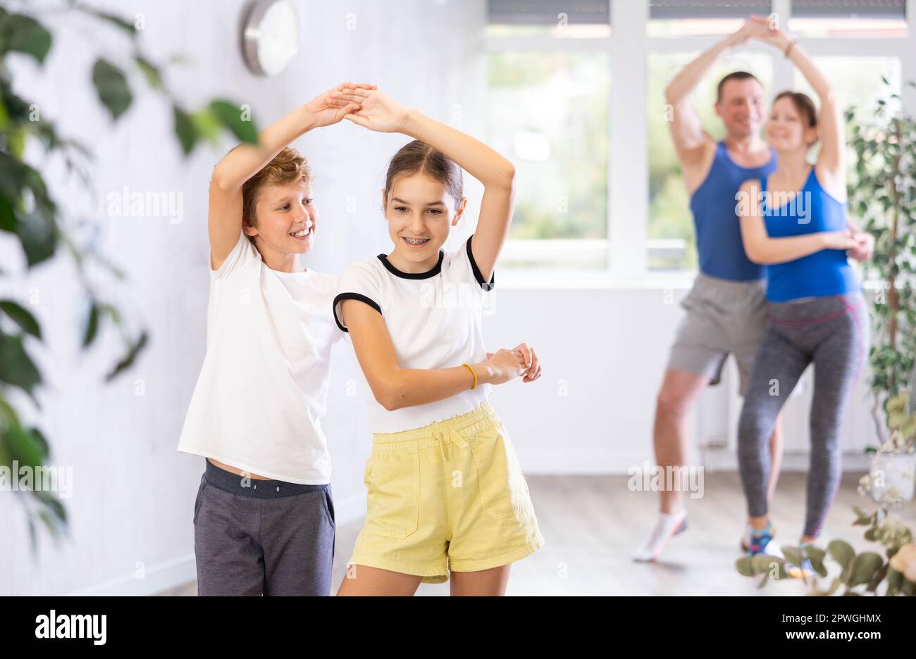 Happy preteen boy and girl practicing dance in pairs together with ...