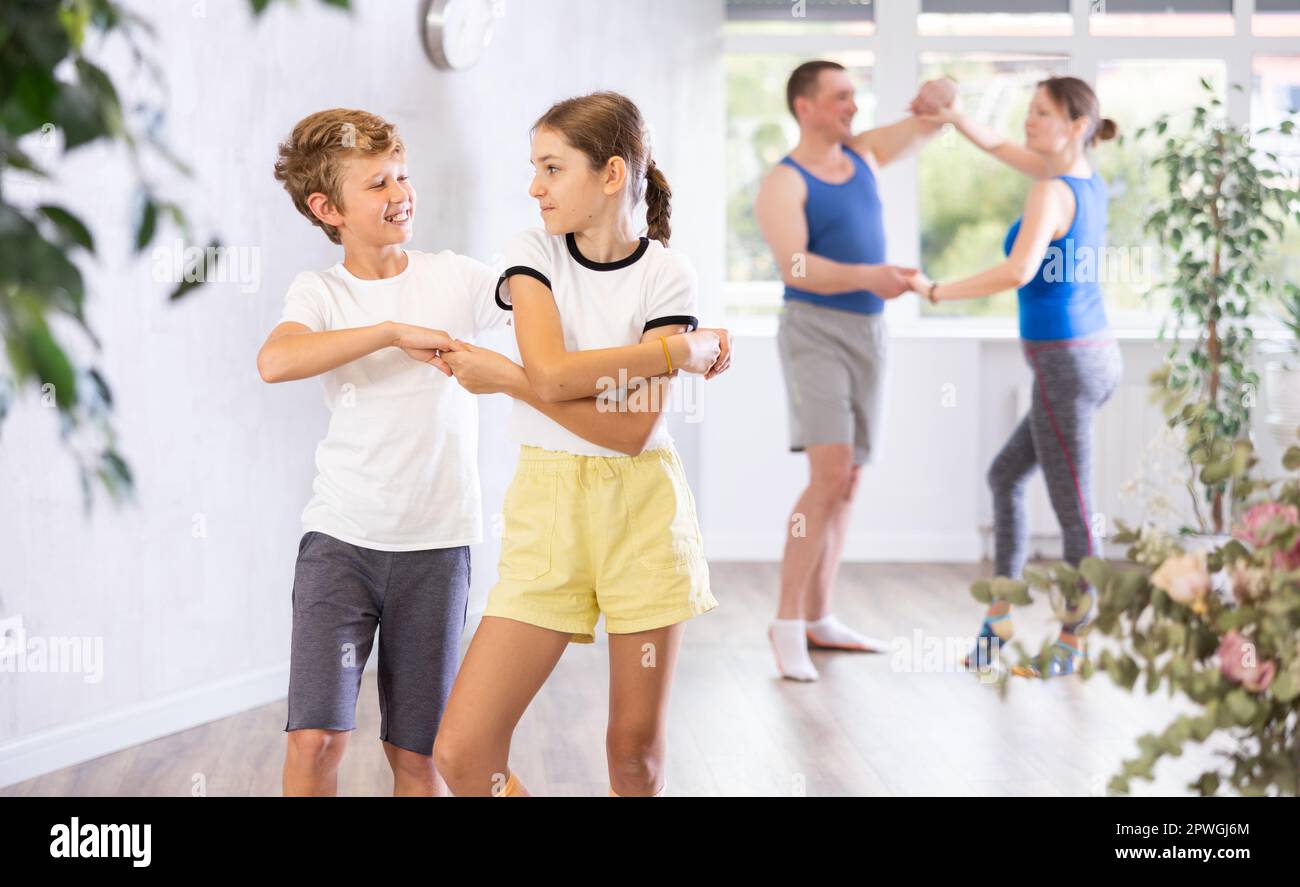 Happy preteen boy and girl practicing dance in pairs together with ...