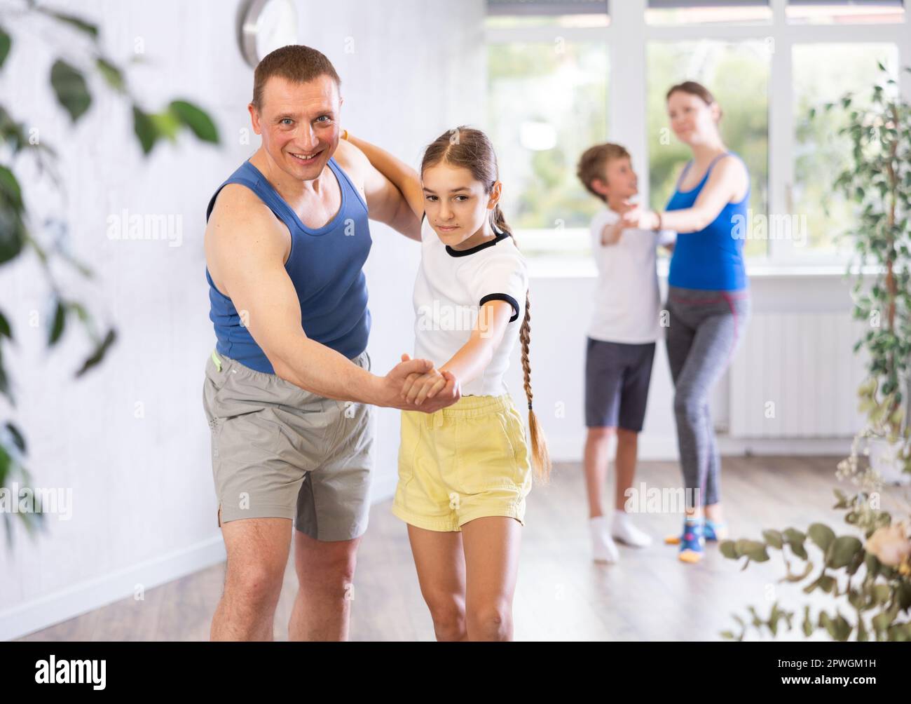 Happy father and daughter practicing dance in pairs together with other ...