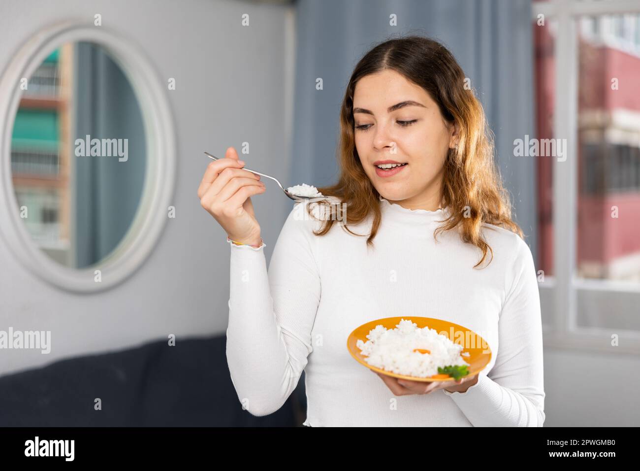 Positive woman keeping diet, eating rice in apartment Stock Photo - Alamy