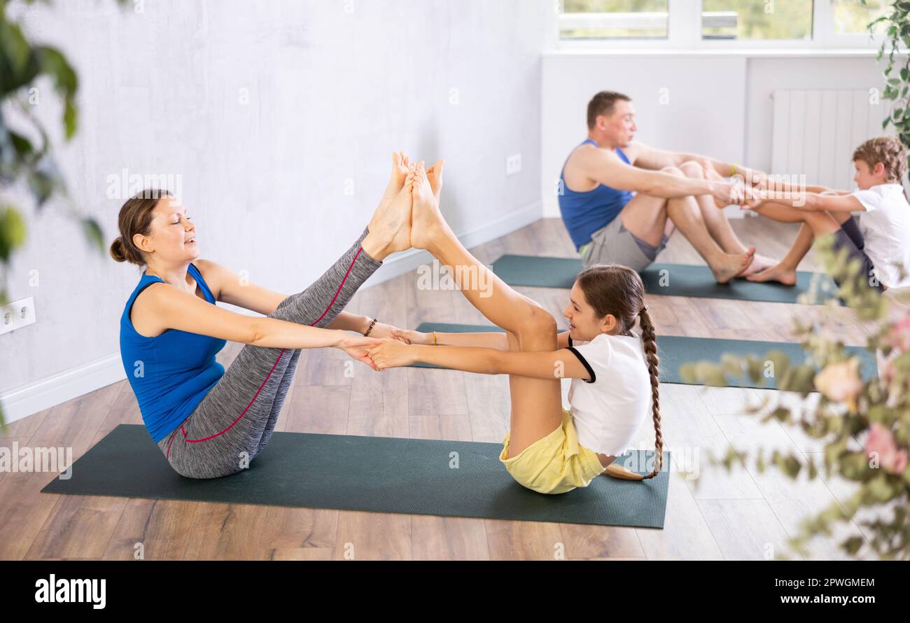 Woman practicing yoga in pair with her teen daughter during family ...