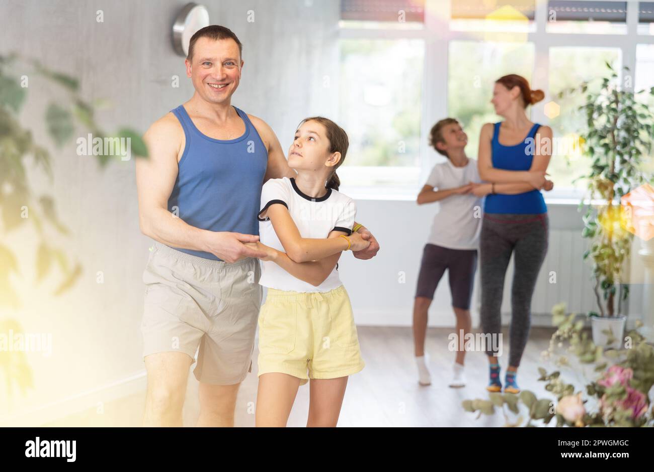 Happy father and daughter practicing dance in pairs together with other ...