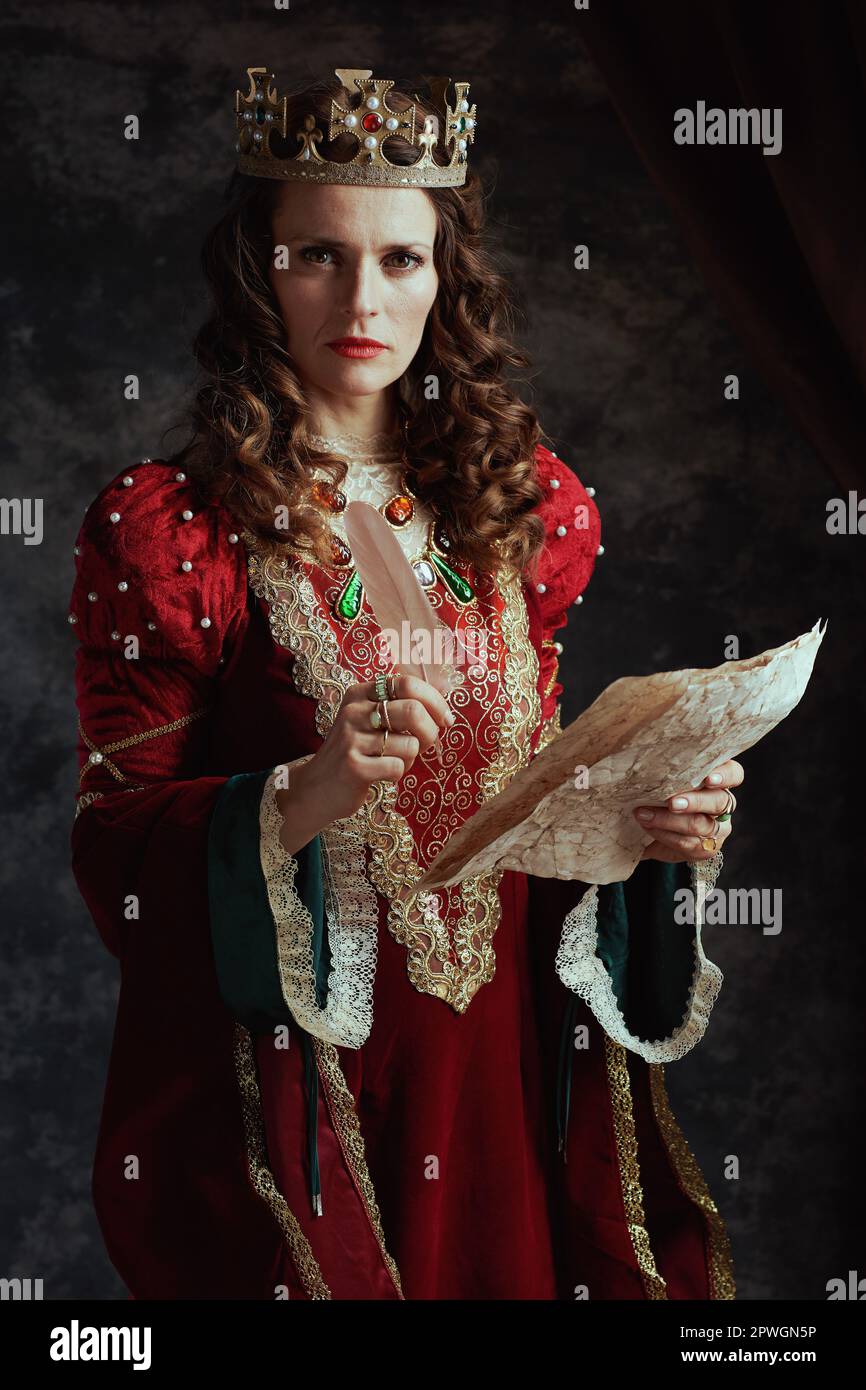 medieval queen in red dress with parchment and crown on dark gray ...