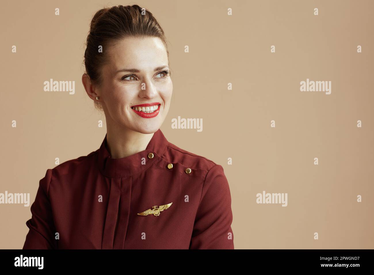 happy stylish female air hostess against beige background looking at ...