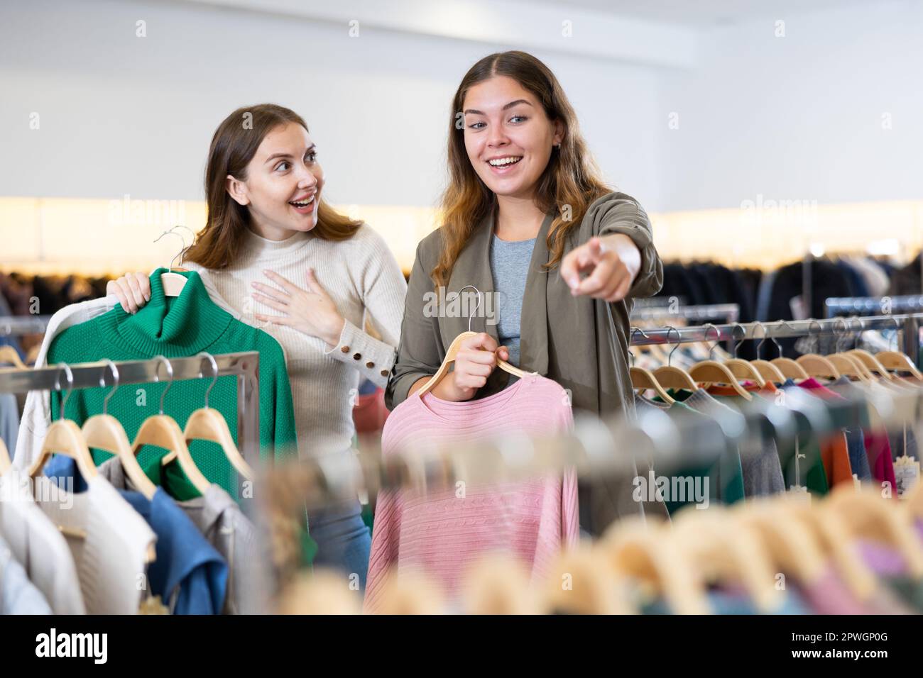 Happy girls pointing finger at new clothes in clothing store Stock ...