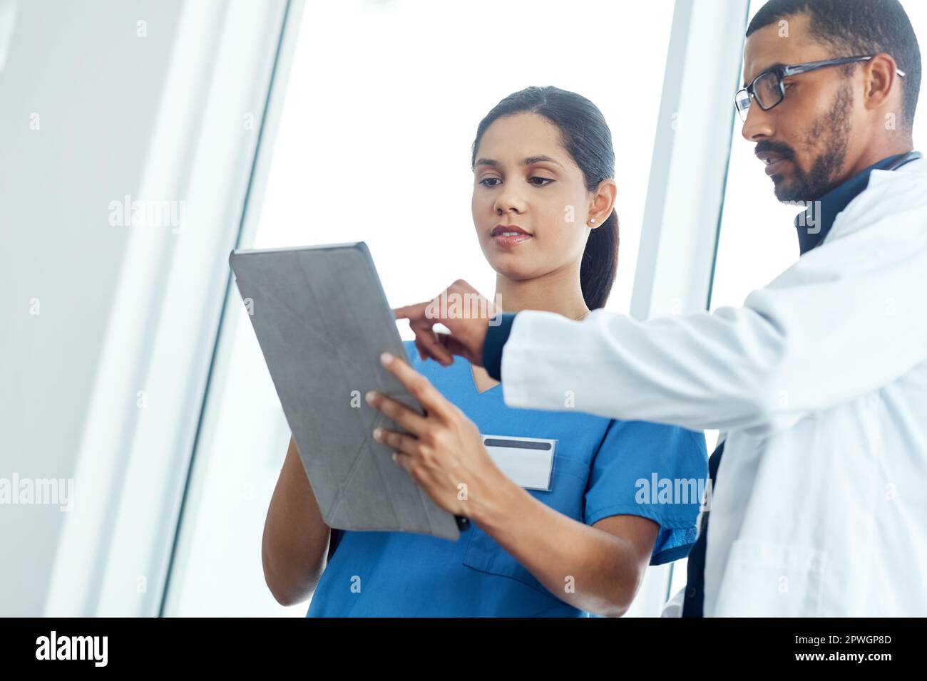 Together theyll reach a diagnosis. two young doctors using a digital ...