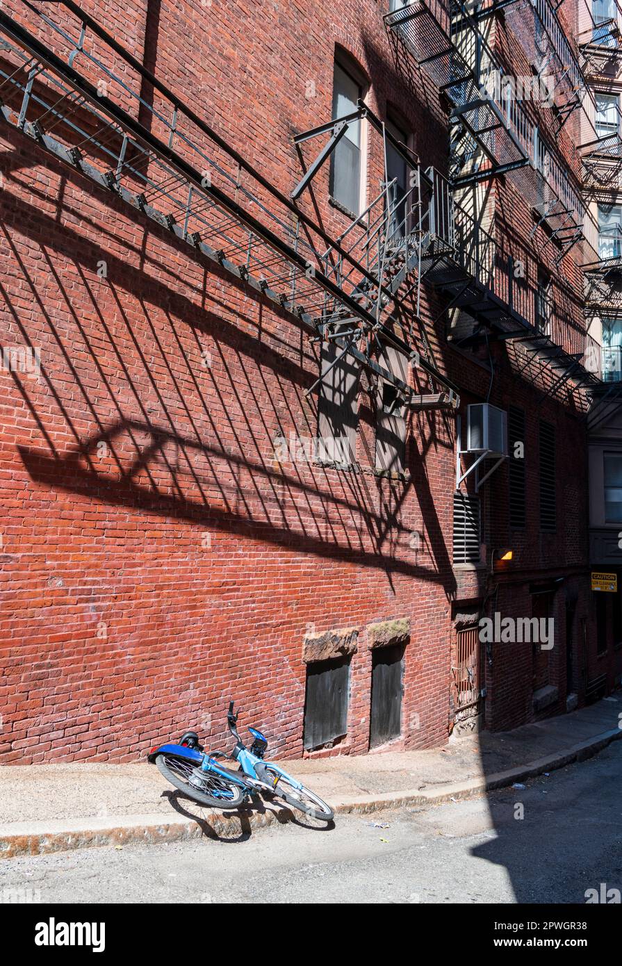 Blue bicycle, dropped at a sidewalk, contrasts with a building red ...