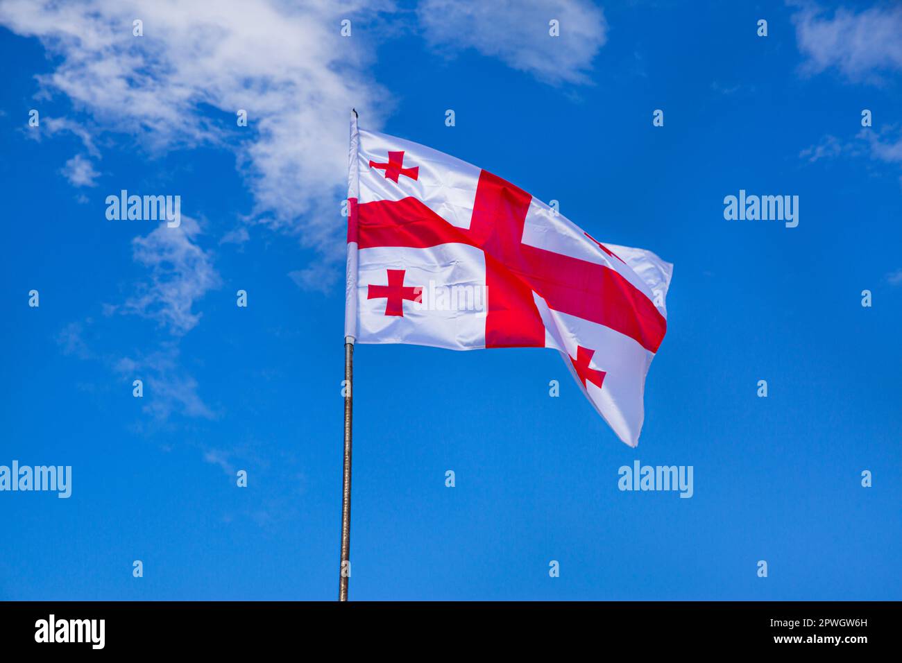 The flague of Georgia waving on bright blue sky background Stock Photo ...