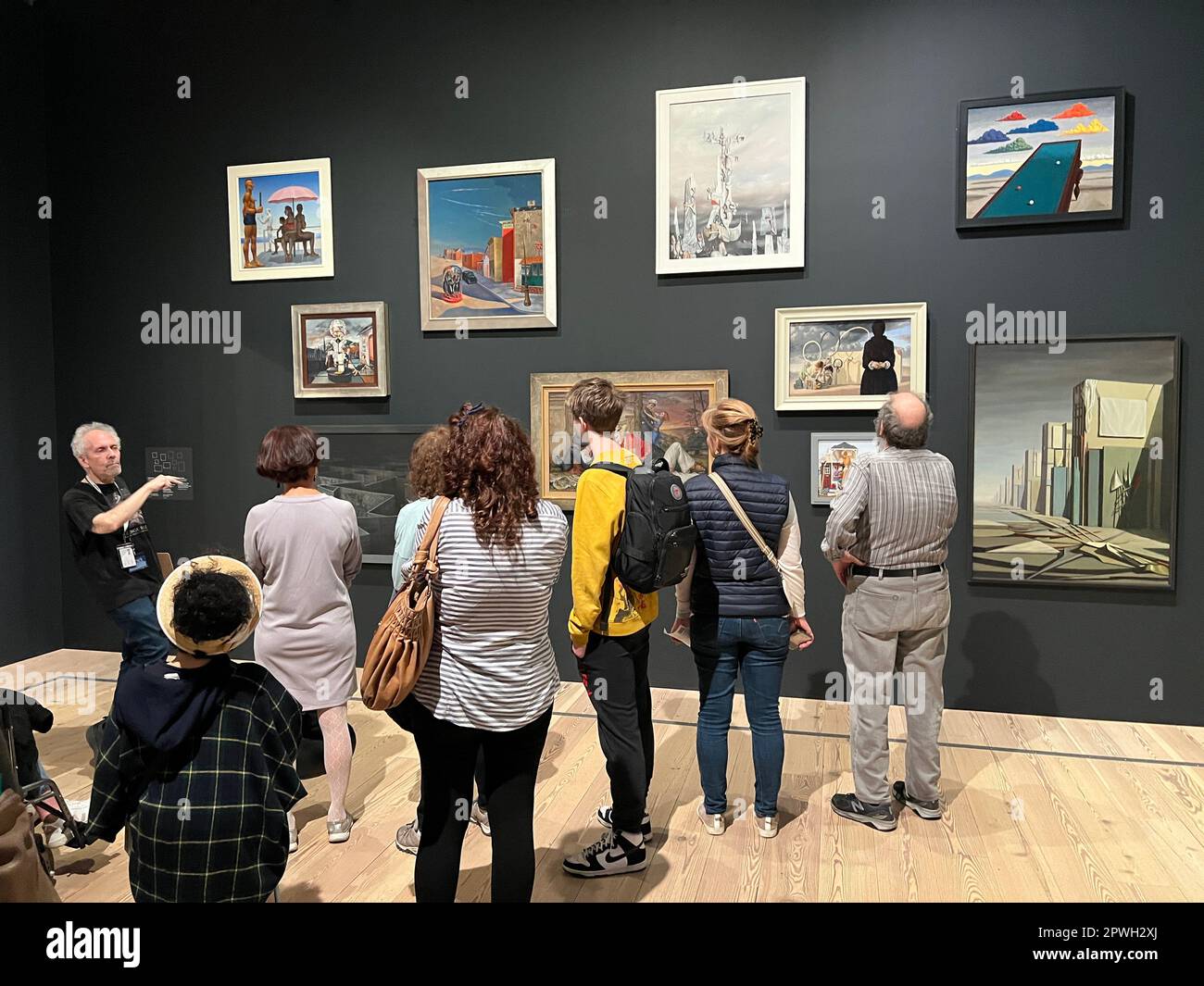 Visitors listen to a museum guide speak about surrealist art and ...