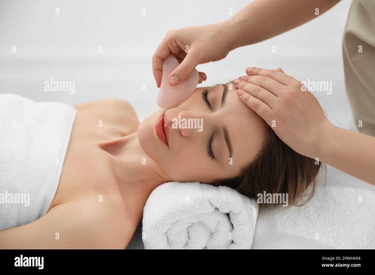 Young woman receiving facial massage with gua sha tool in beauty salon Stock Photo - Alamy