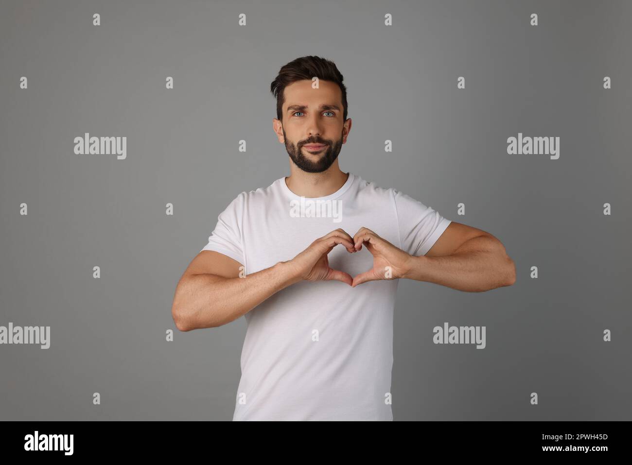 Man making heart with hands on grey background Stock Photo - Alamy