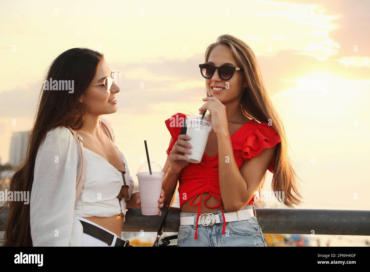 Beautiful young women with tasty milk shakes outdoors Stock Photo - Alamy