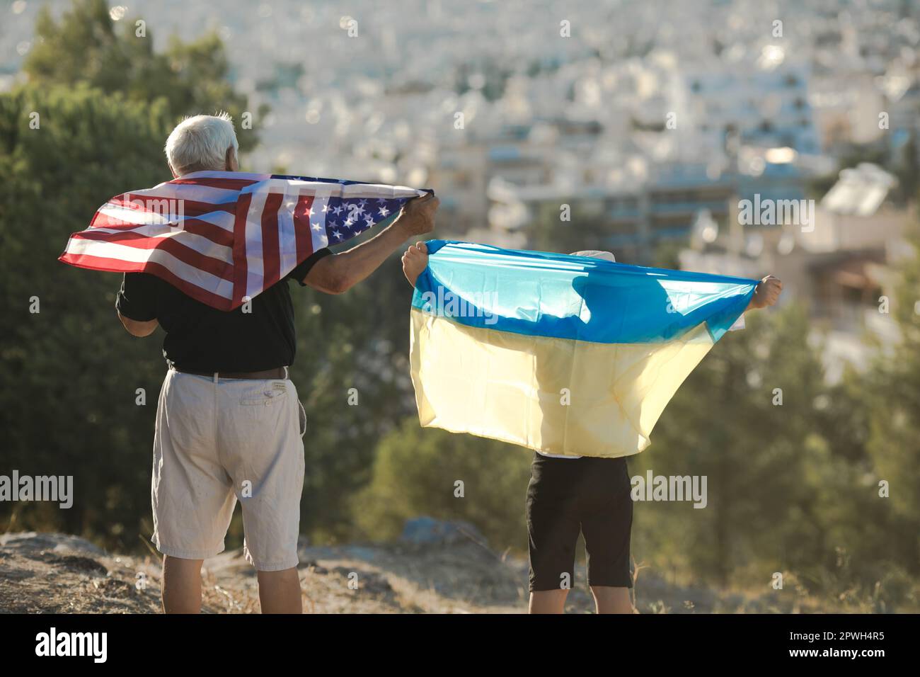 Retired man and kid boy holding the flags of the USA and Ukraine on ...