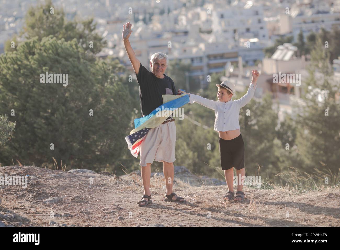 Retired man and kid boy holding the flags of the USA and Ukraine on ...