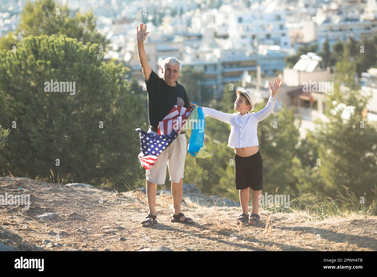 Retired man and kid boy holding the flags of the USA and Ukraine on ...