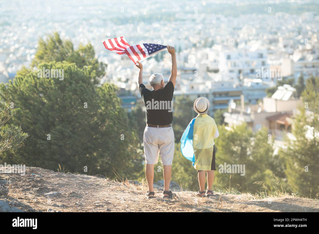 Retired man and kid boy holding the flags of the USA and Ukraine on ...