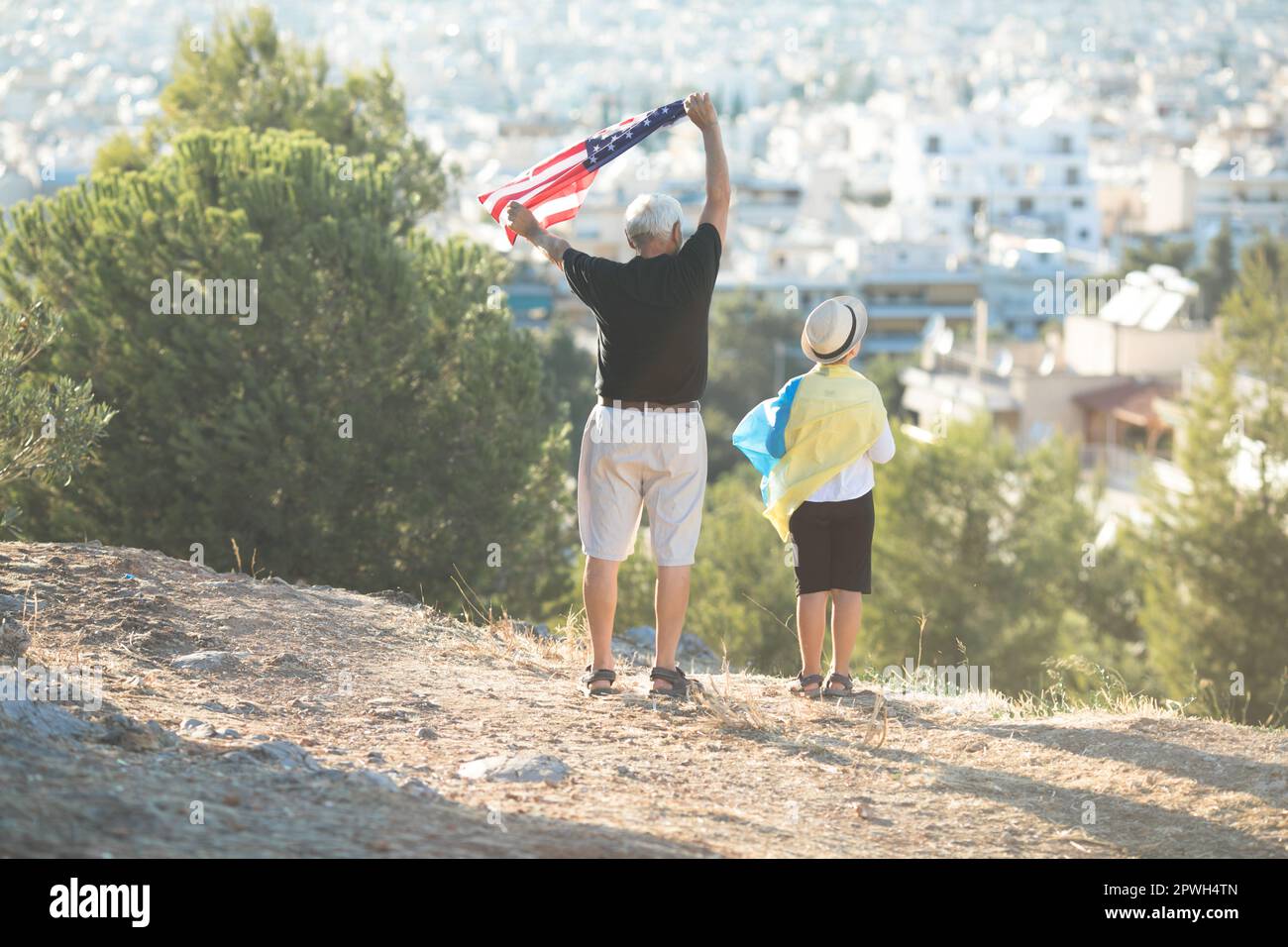 Retired man and kid boy holding the flags of the USA and Ukraine on ...