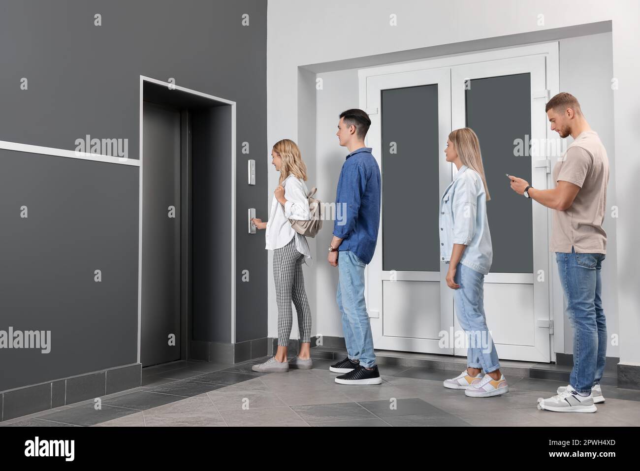 Group of people waiting in line for elevator while woman pressing call ...