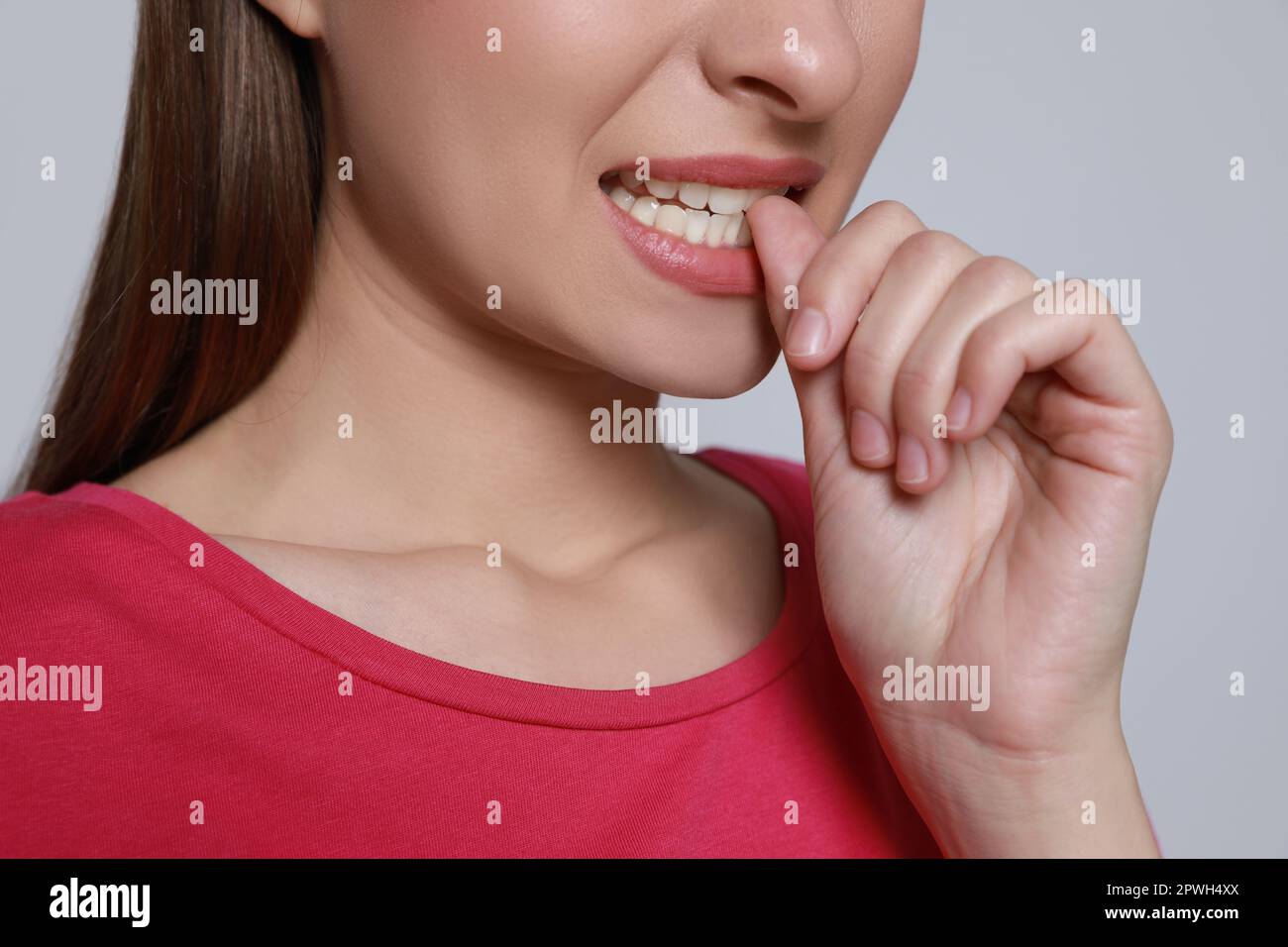 Young woman biting her nails on light grey background, closeup Stock ...