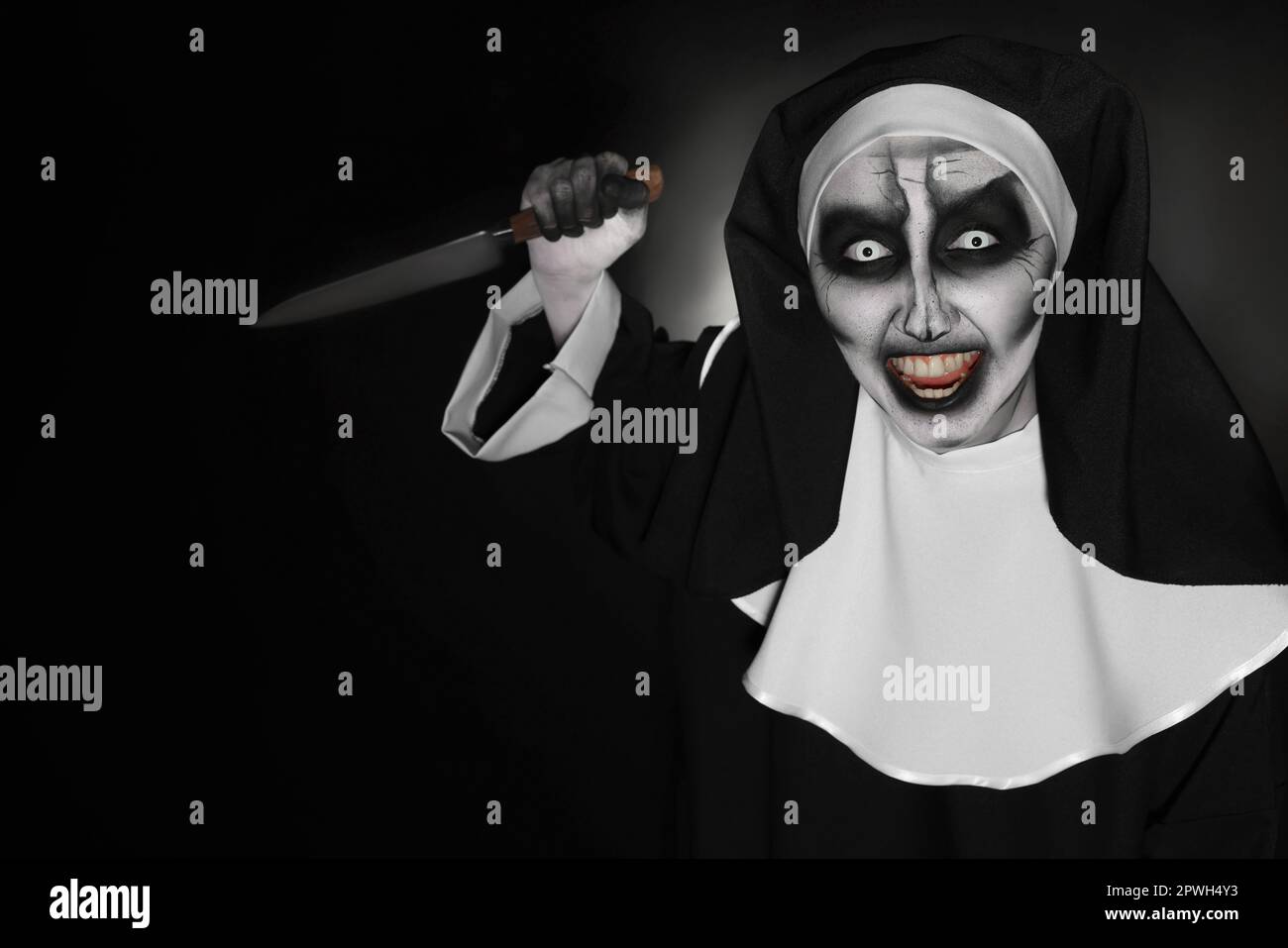 Scary devilish nun with knife on black background, space for text ...