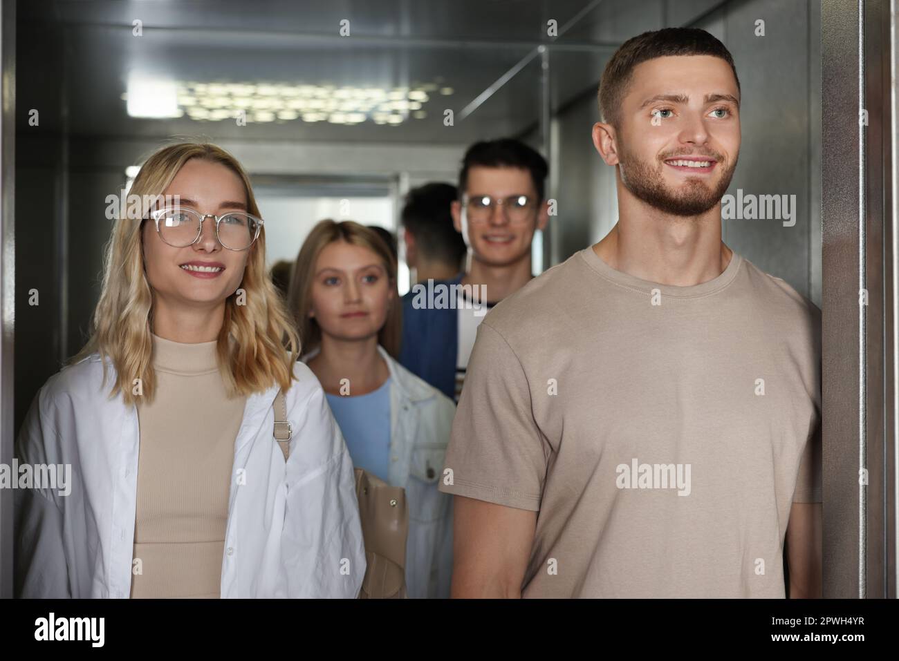 Group of young people in modern elevator Stock Photo - Alamy