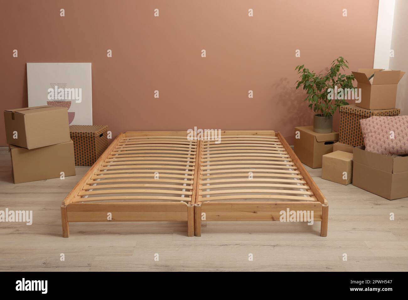 Wooden bed frame and cardboard boxes on floor in room Stock Photo - Alamy