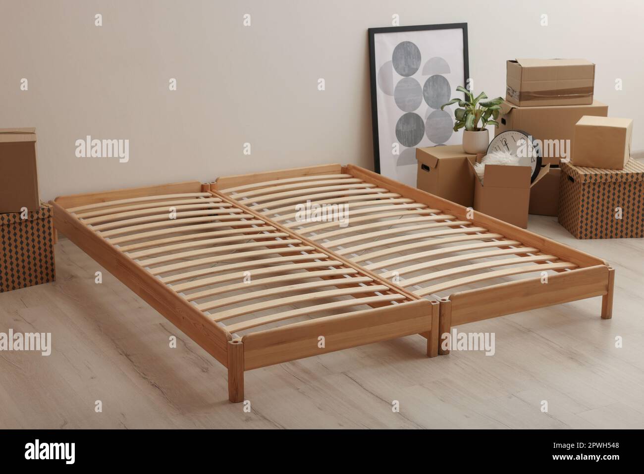 Wooden bed frame and cardboard boxes on floor in room Stock Photo - Alamy