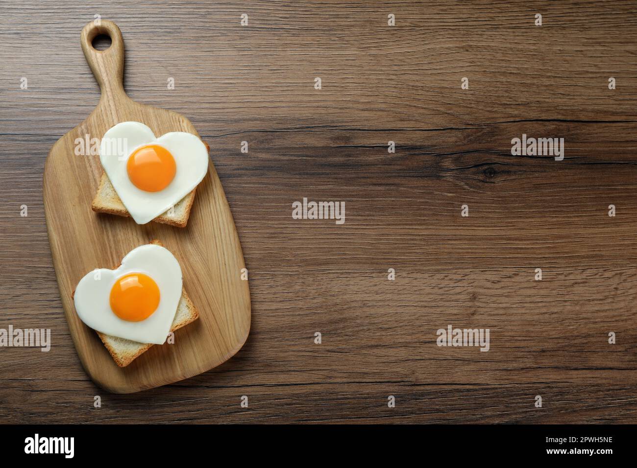 Heart shaped fried eggs and toasts on wooden table, top view. Space for text Stock Photo - Alamy