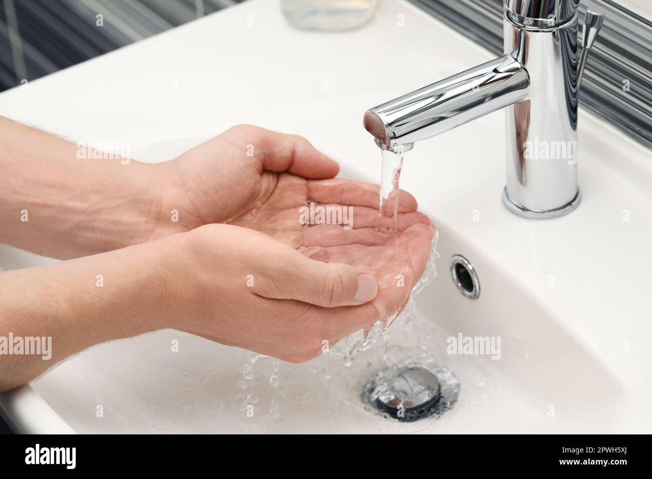 Man using water tap to wash hands in bathroom, closeup Stock Photo - Alamy
