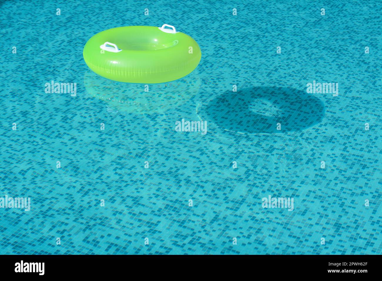 Light green inflatable ring floating in swimming pool. space for text ...