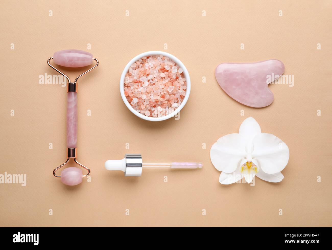 Flat lay composition with gua sha stone and face roller on beige ...
