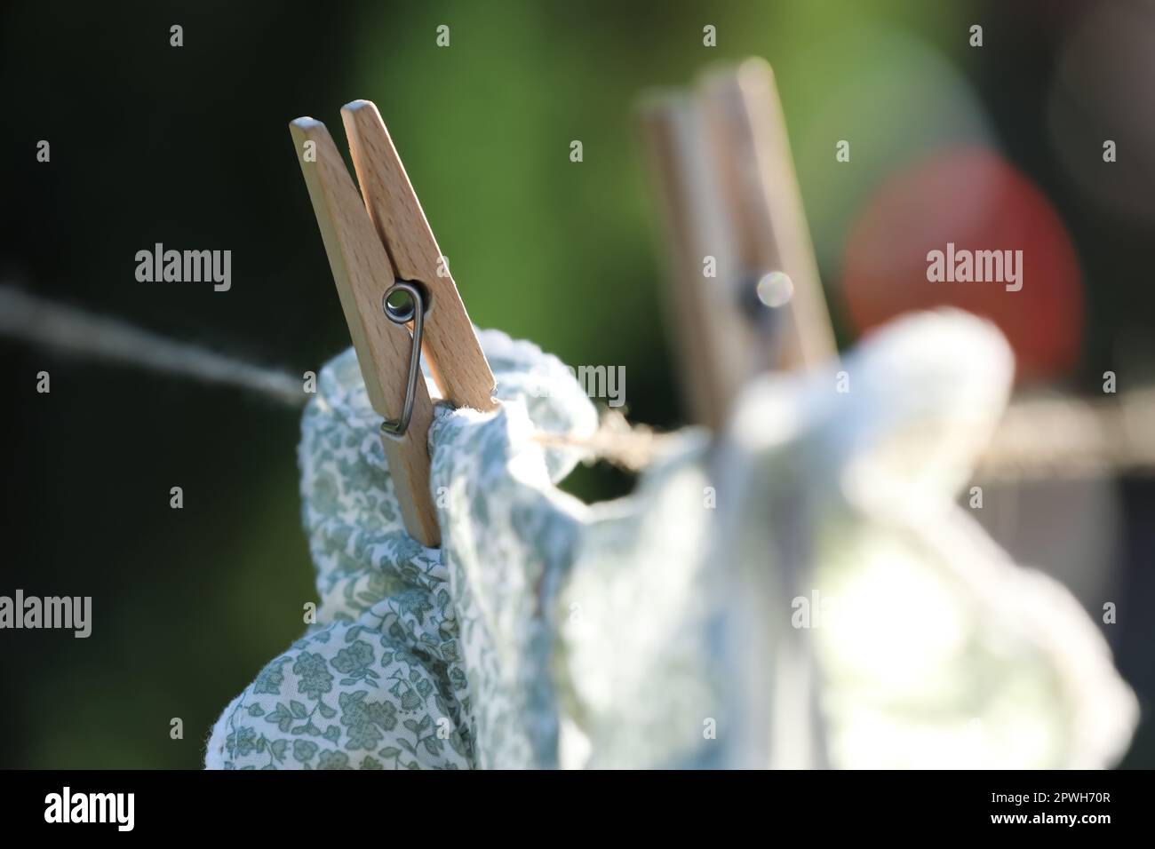 Washing line with drying dress against blurred background, focus on clothespin Stock Photo - Alamy