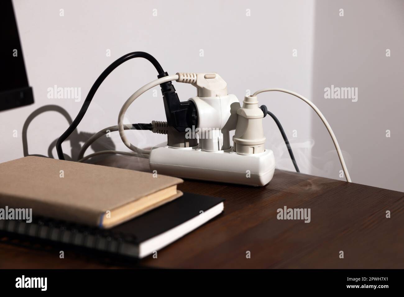Smoking plug in power strip on wooden table. Electrical short circuit ...