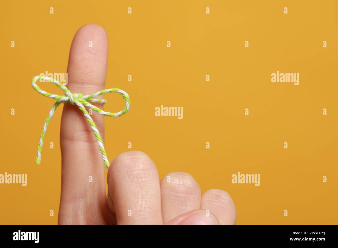 Woman showing index finger with tied bow as reminder on orange ...
