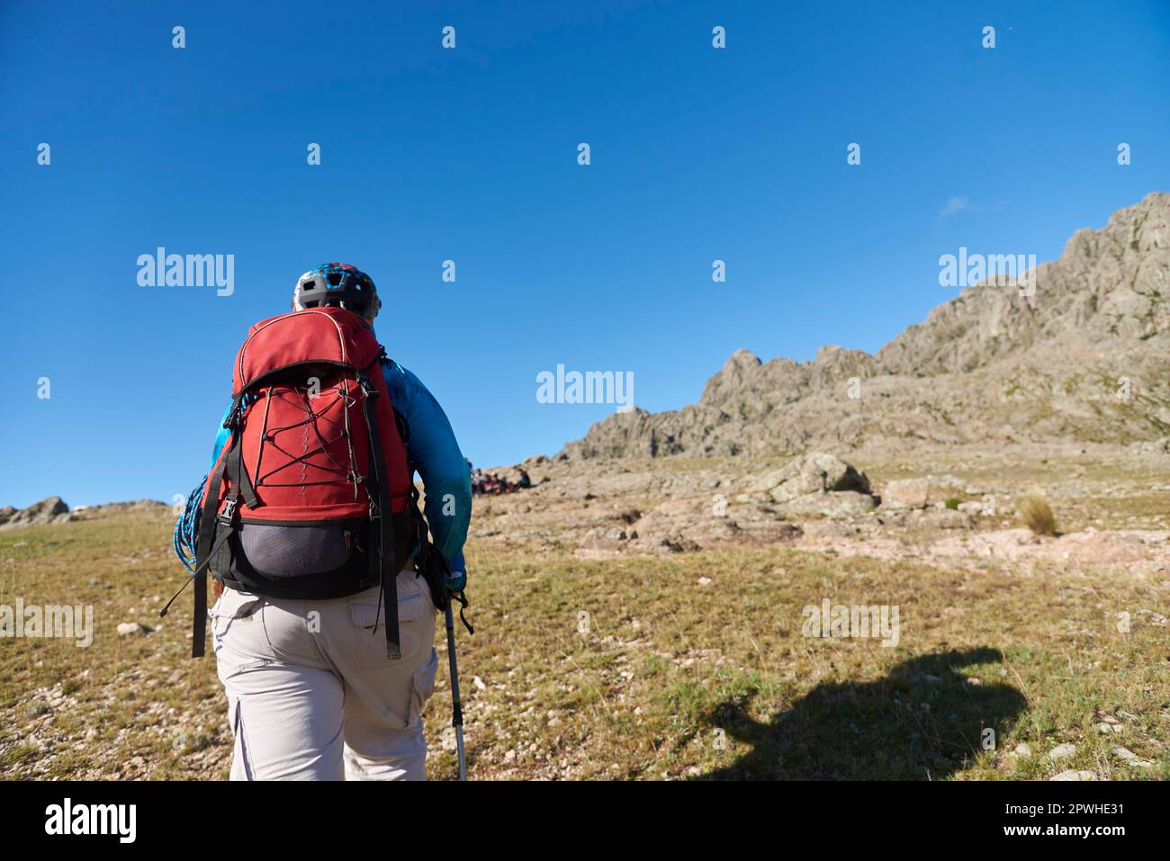 Unrecognizable mountaineer hiking up a trail amidst a rocky mountain ...
