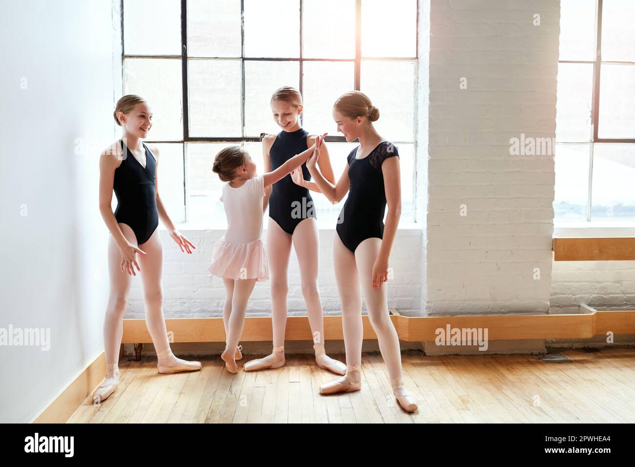 Practice made perfect. a group of young ballerinas giving each other a ...