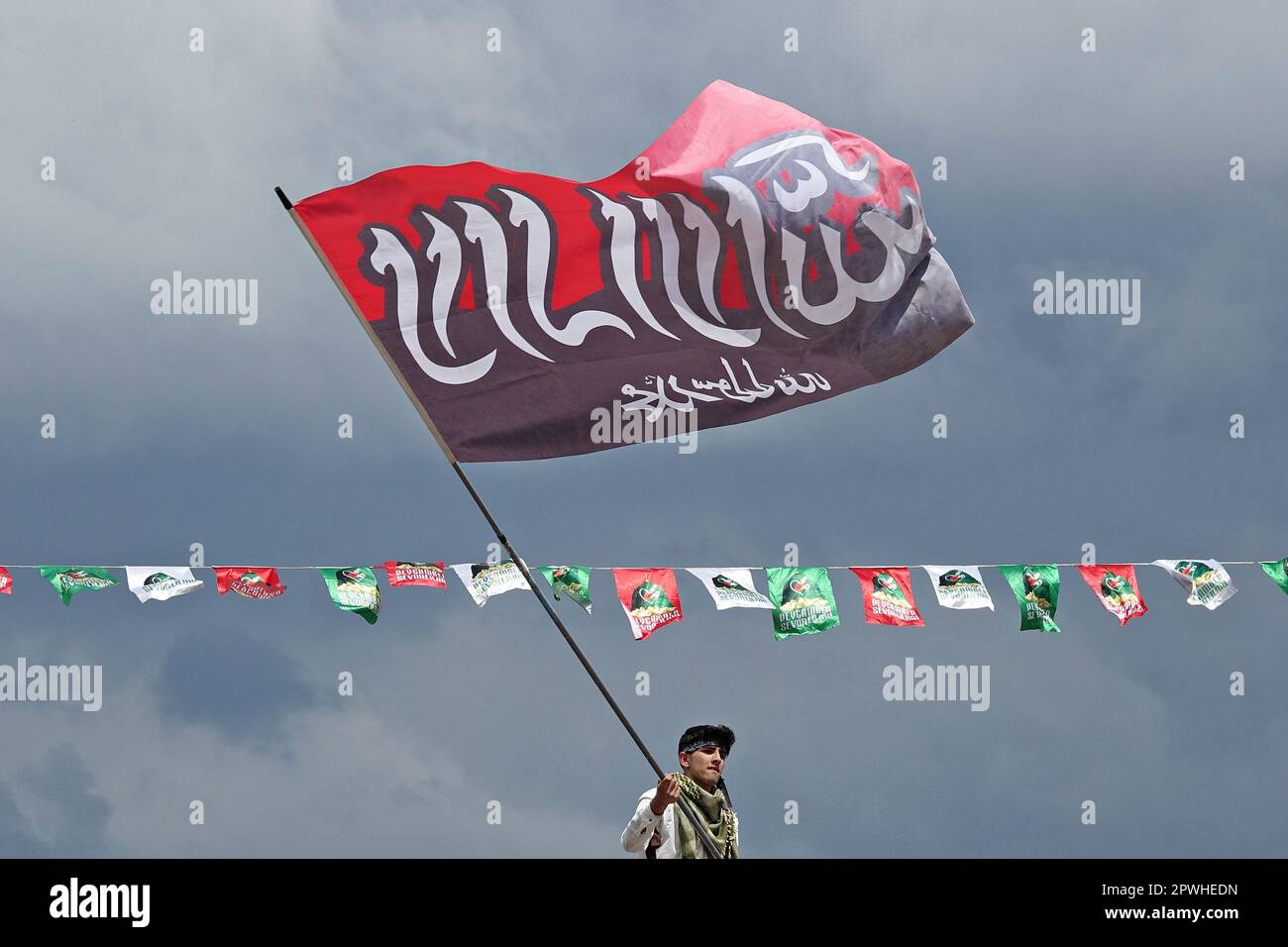A young man seen waving an inscribed flag, "There is no god but Allah ...