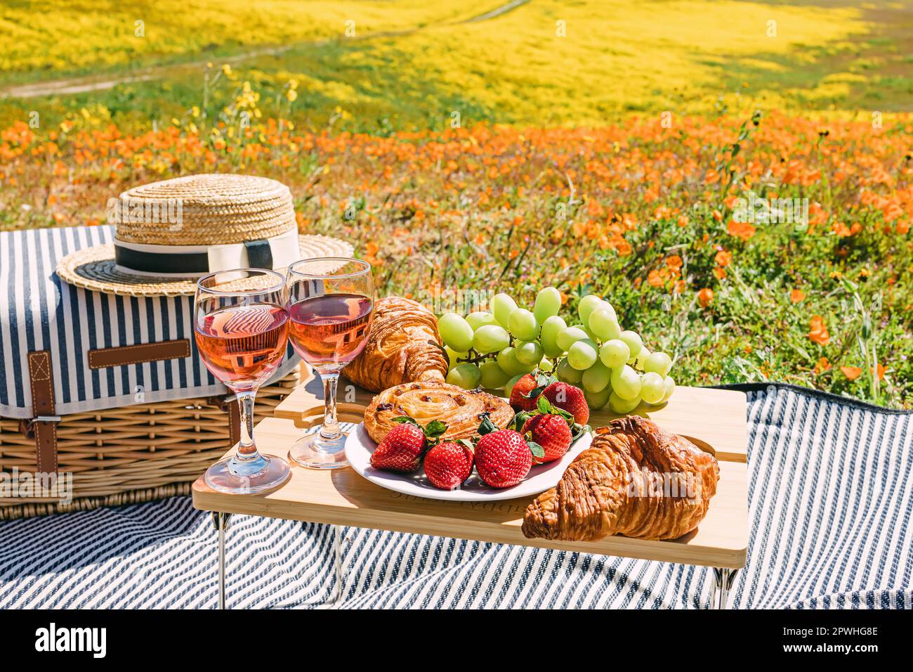 Romantic spring picnic on the flower meadow, rose wine strawberry and ...