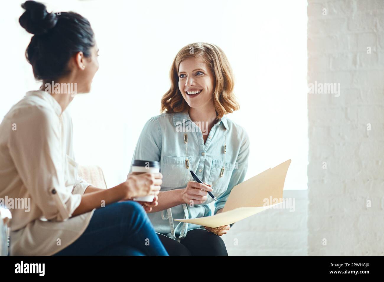They work well together. two young businesswomen looking over some ...