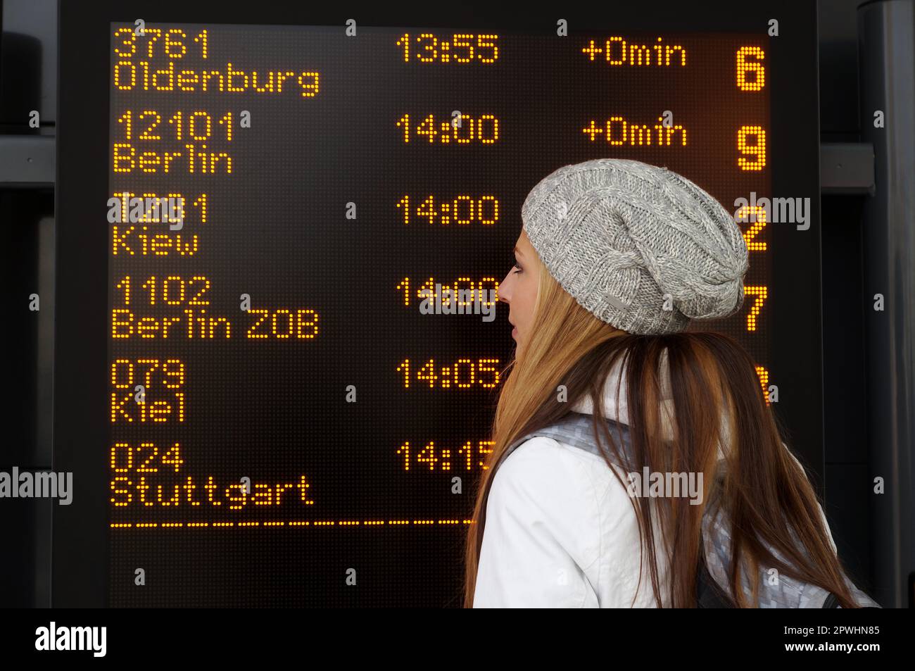 Young woman stands in front of a display board with departure times at ...