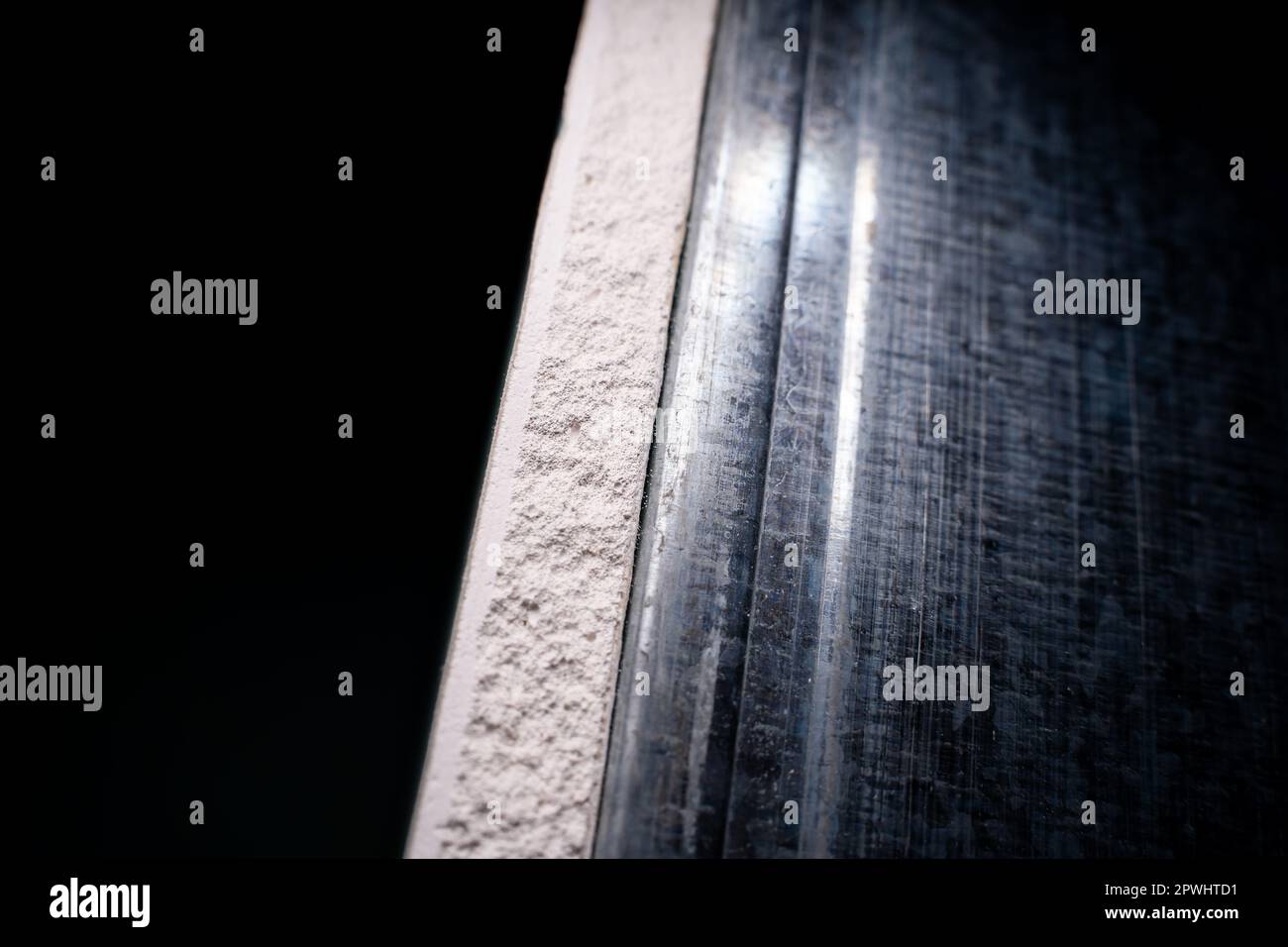 Close-up cut of drywall screwed to a metal profile on a dark background ...