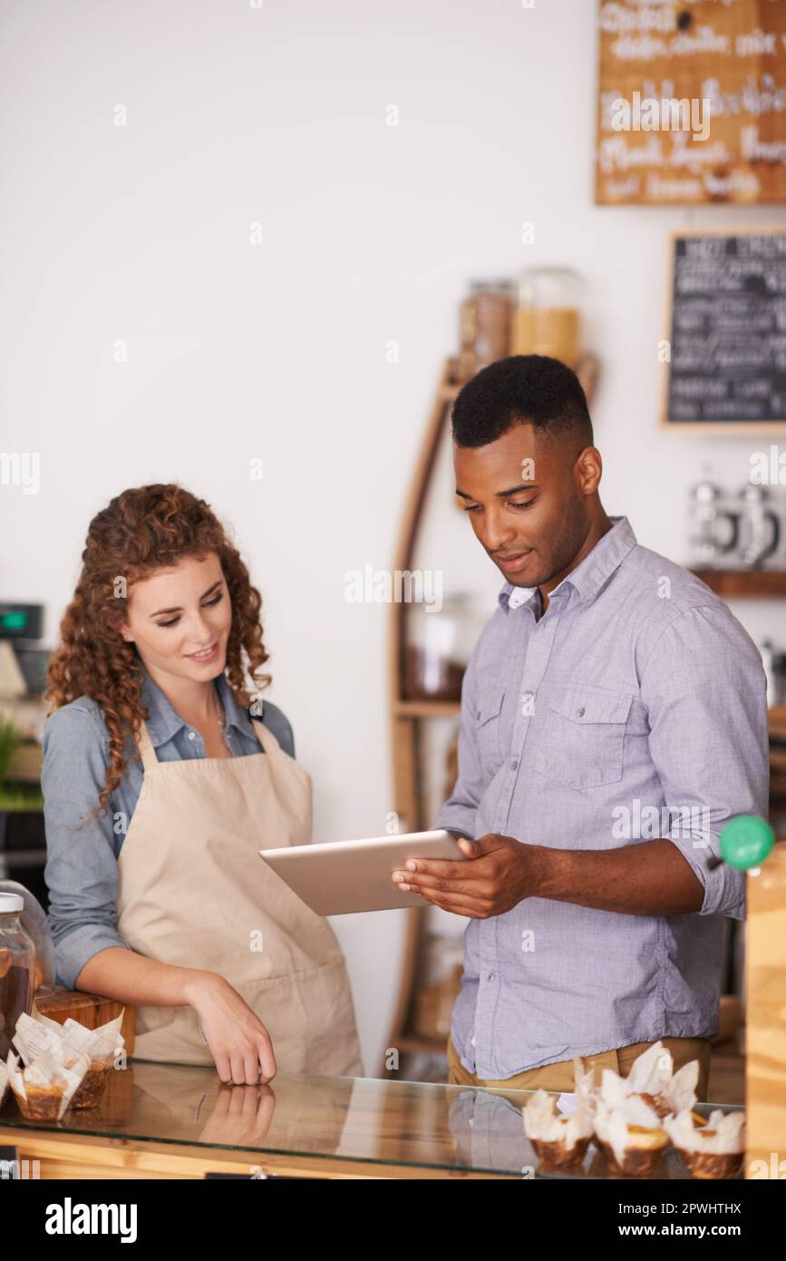 Tablet, coffee shop and barista teamwork of people in discussion and ...